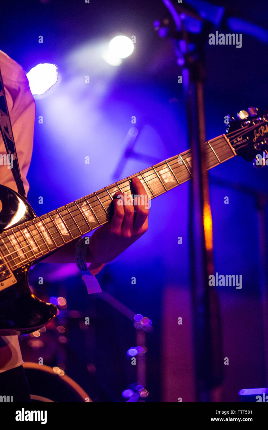 Cropped hand of male singer singing and playing guitar in nightclub ...