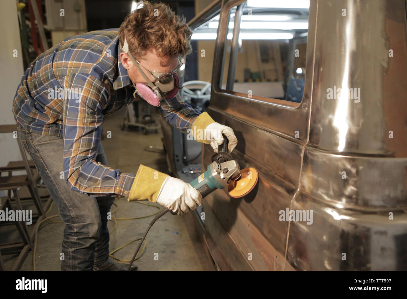 Engineer polishing van with angle grinder in factory Stock Photo - Alamy