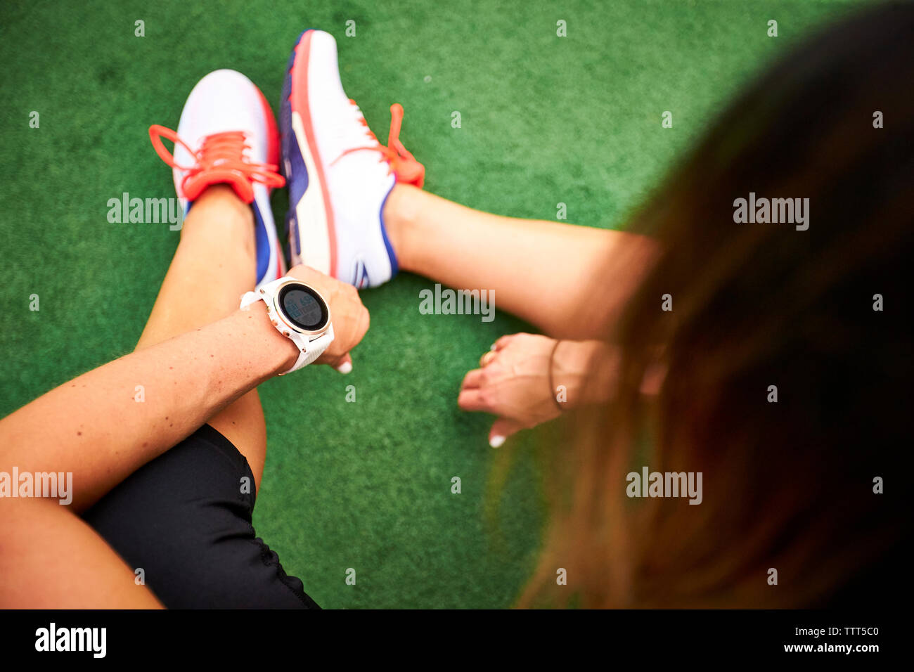 An overhead view of an athletic woman looking at her fitness watch ...