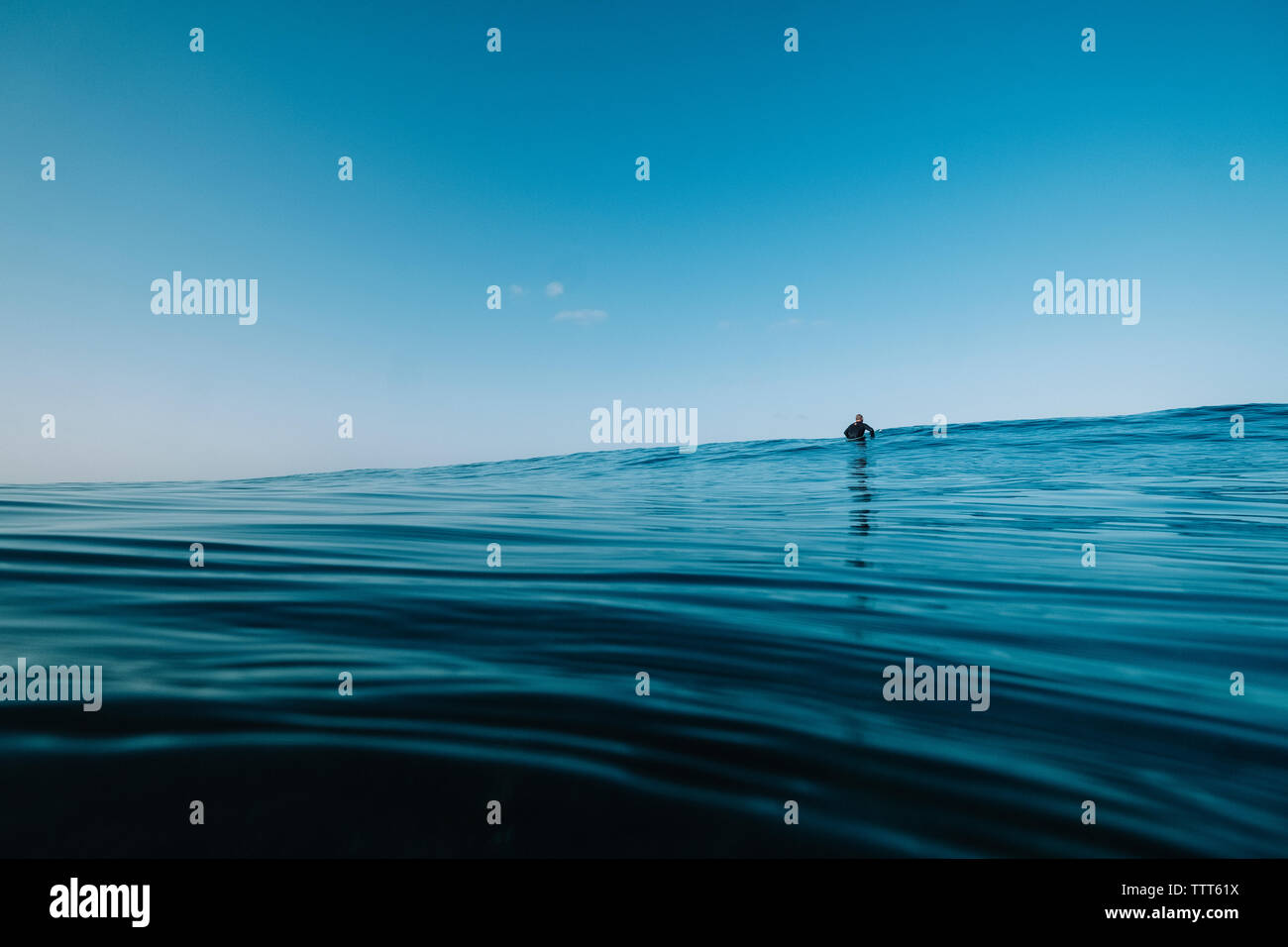 Pulled-back view of a surfer waiting for a wave on his surfboard Stock ...