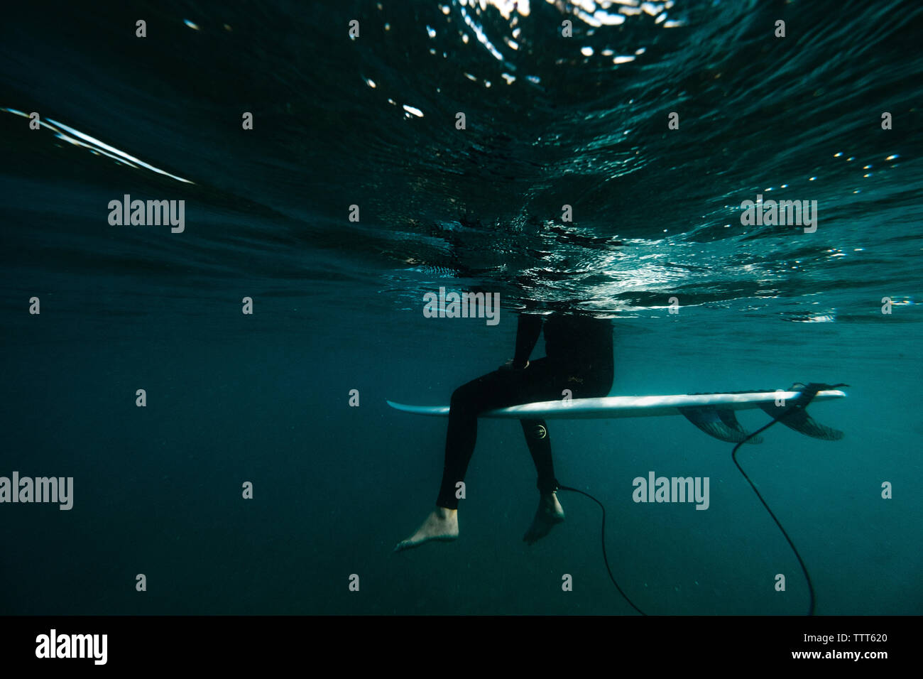 Underwater view of a surfer sitting on his board Stock Photo - Alamy