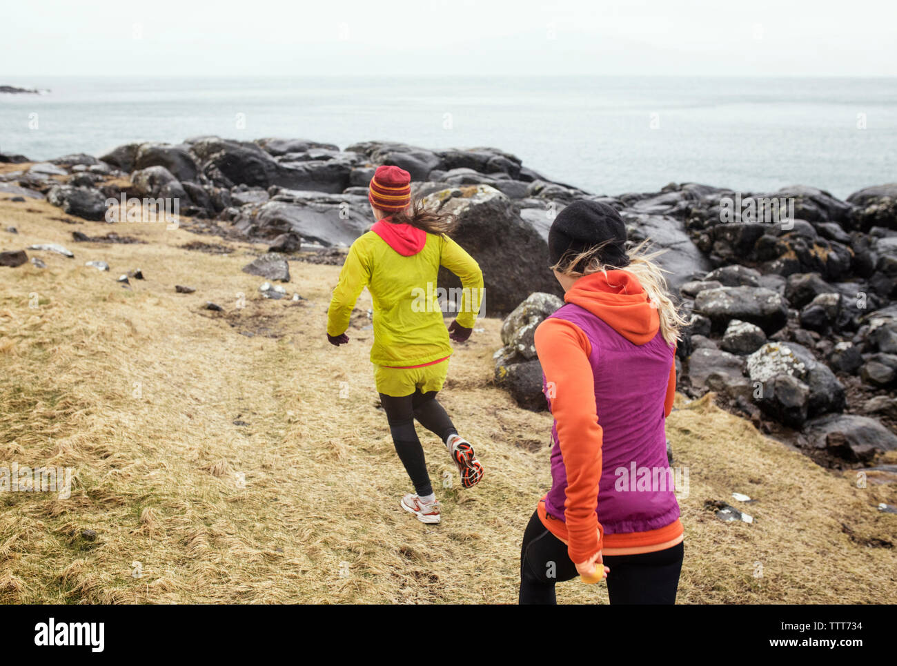 Friends running on field by shore Stock Photo - Alamy
