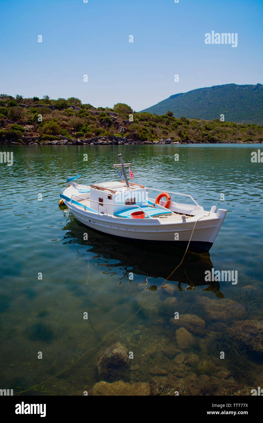 Empty boat moored in lake against clear sky Stock Photo - Alamy