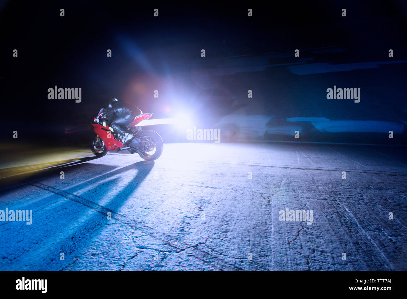 Biker riding motorcycle on road at night Stock Photo - Alamy