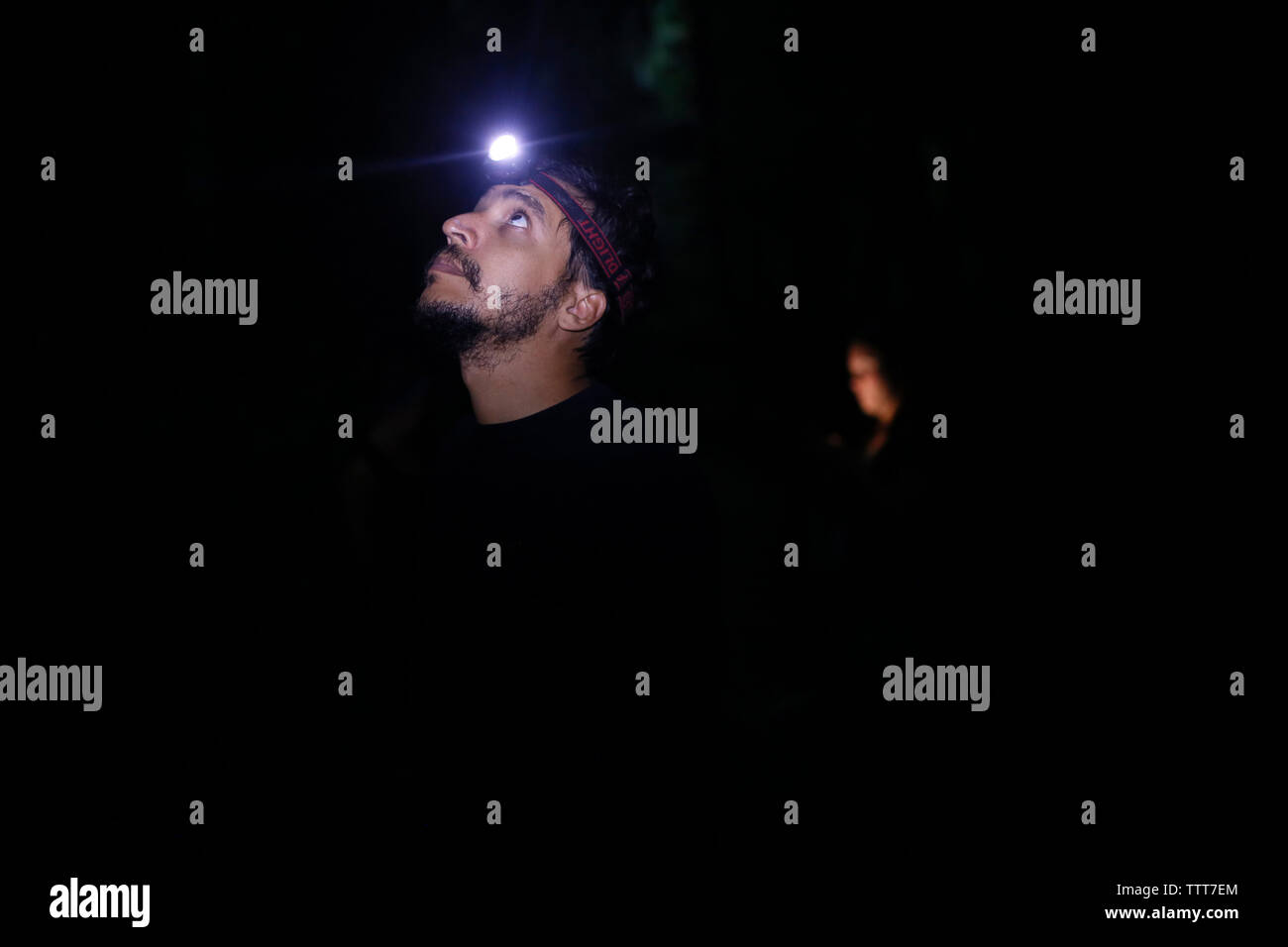 Man looking up while wearing headlamp at night Stock Photo - Alamy