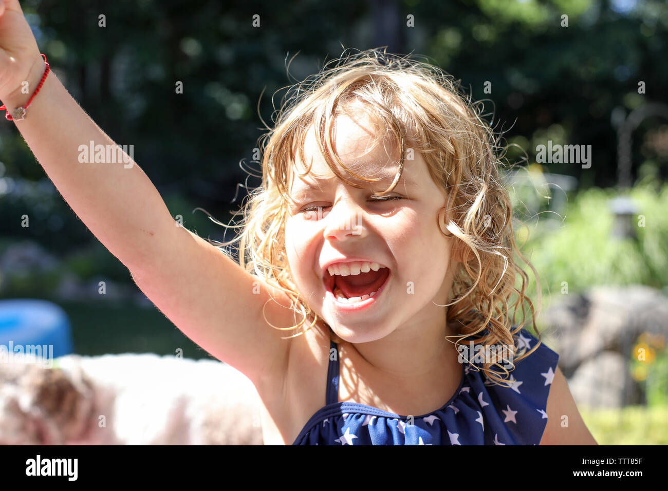 Close-up of happy girl with hand raised screaming while standing in yard Stock Photo - Alamy