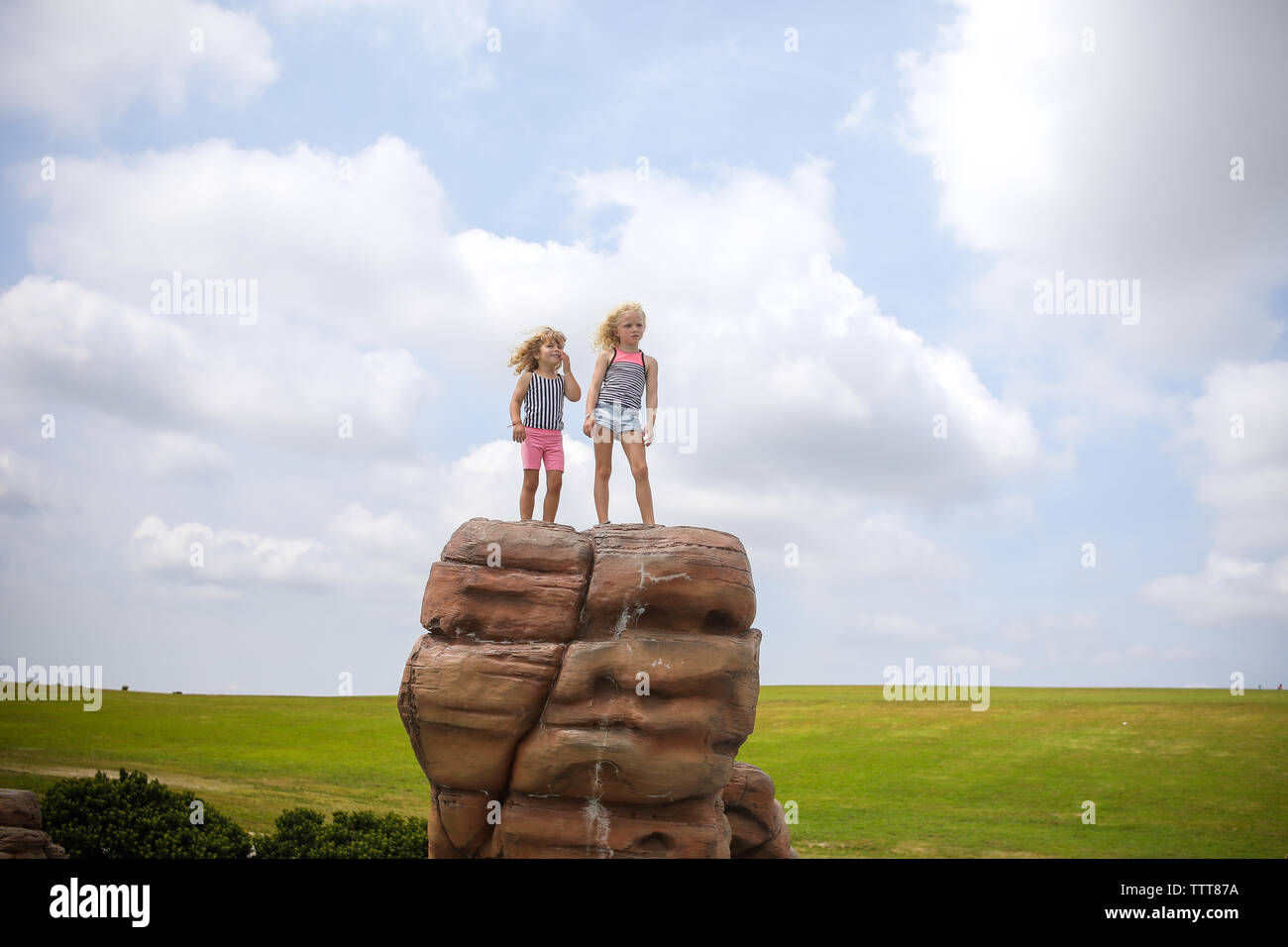 little girls standing on top of rocks in striped shirt blue skies Stock ...