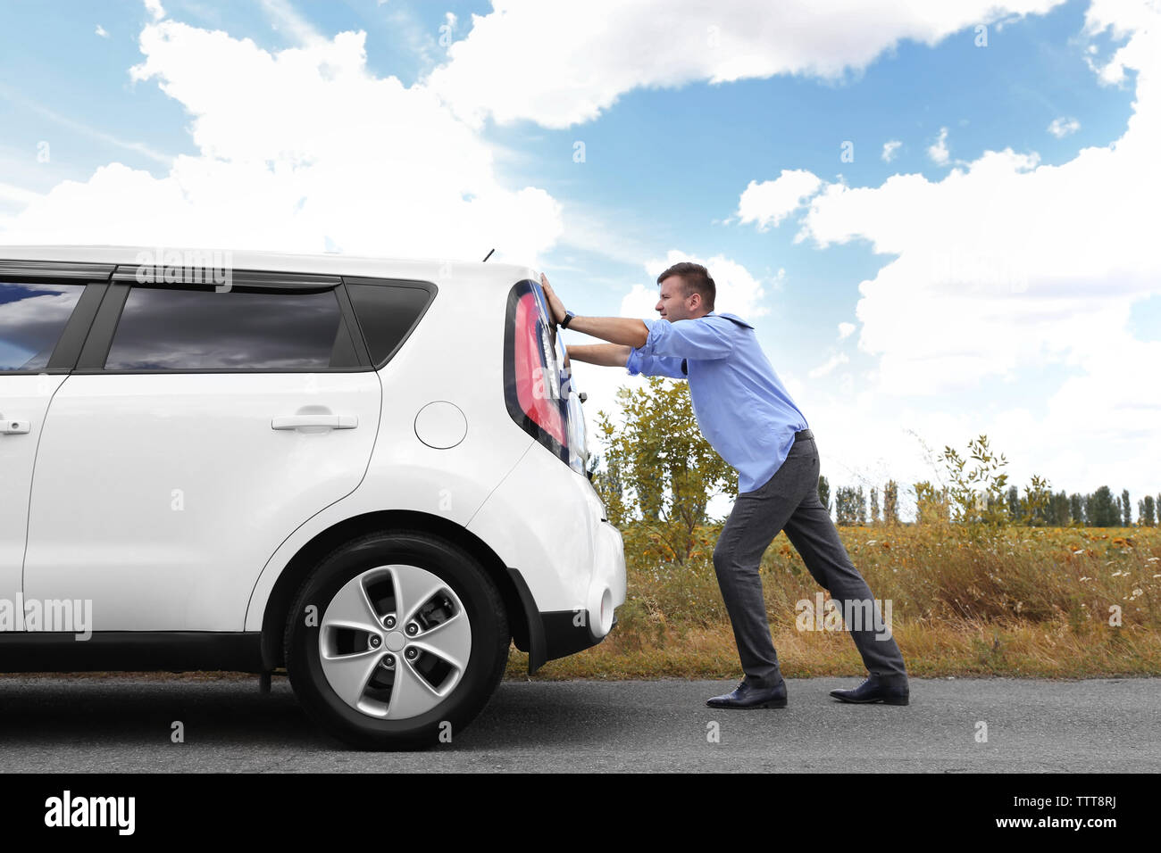 Man pushing damaged car Stock Photo - Alamy