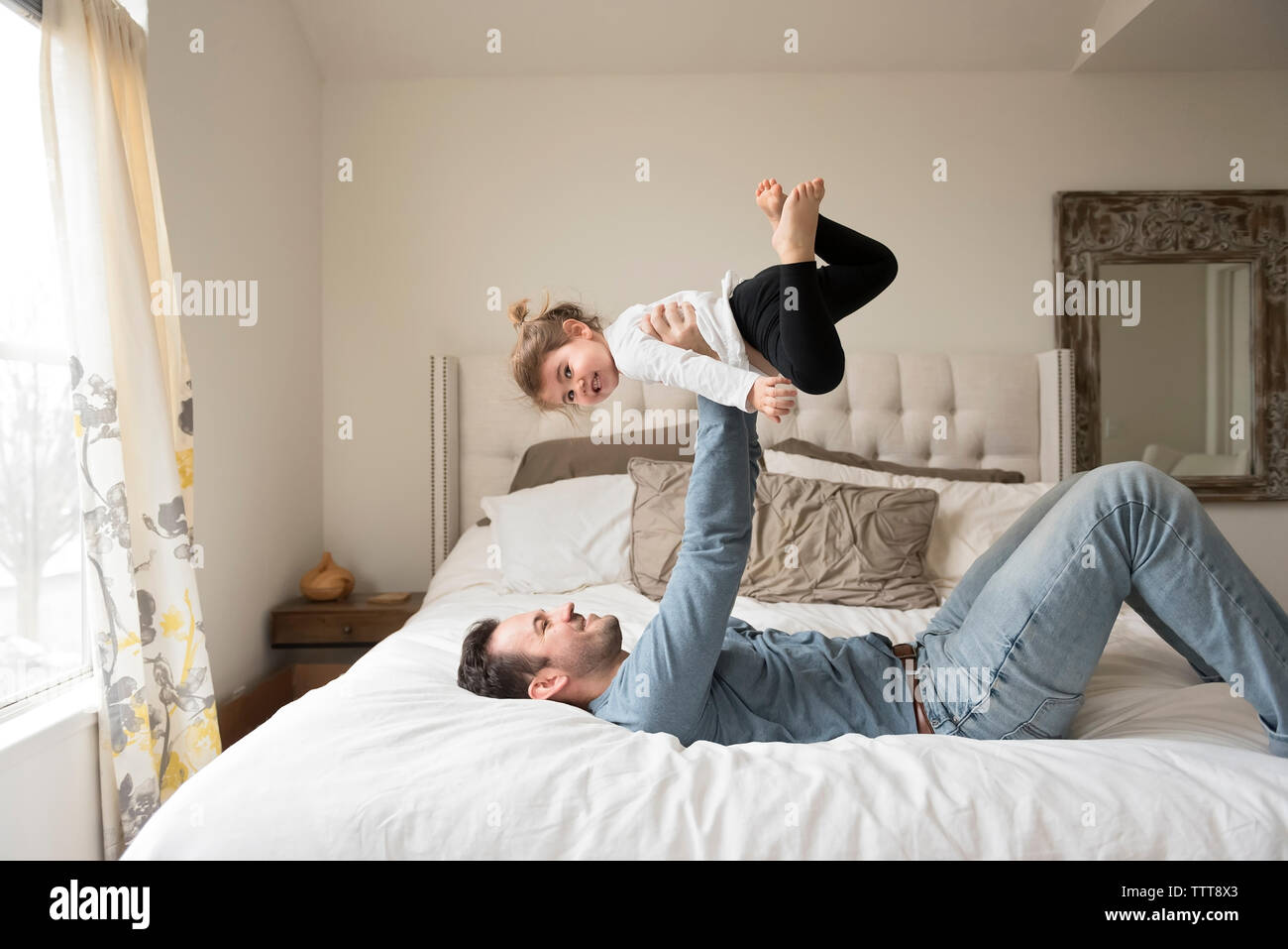 Playful father lifting daughter while on bed at home Stock Photo - Alamy
