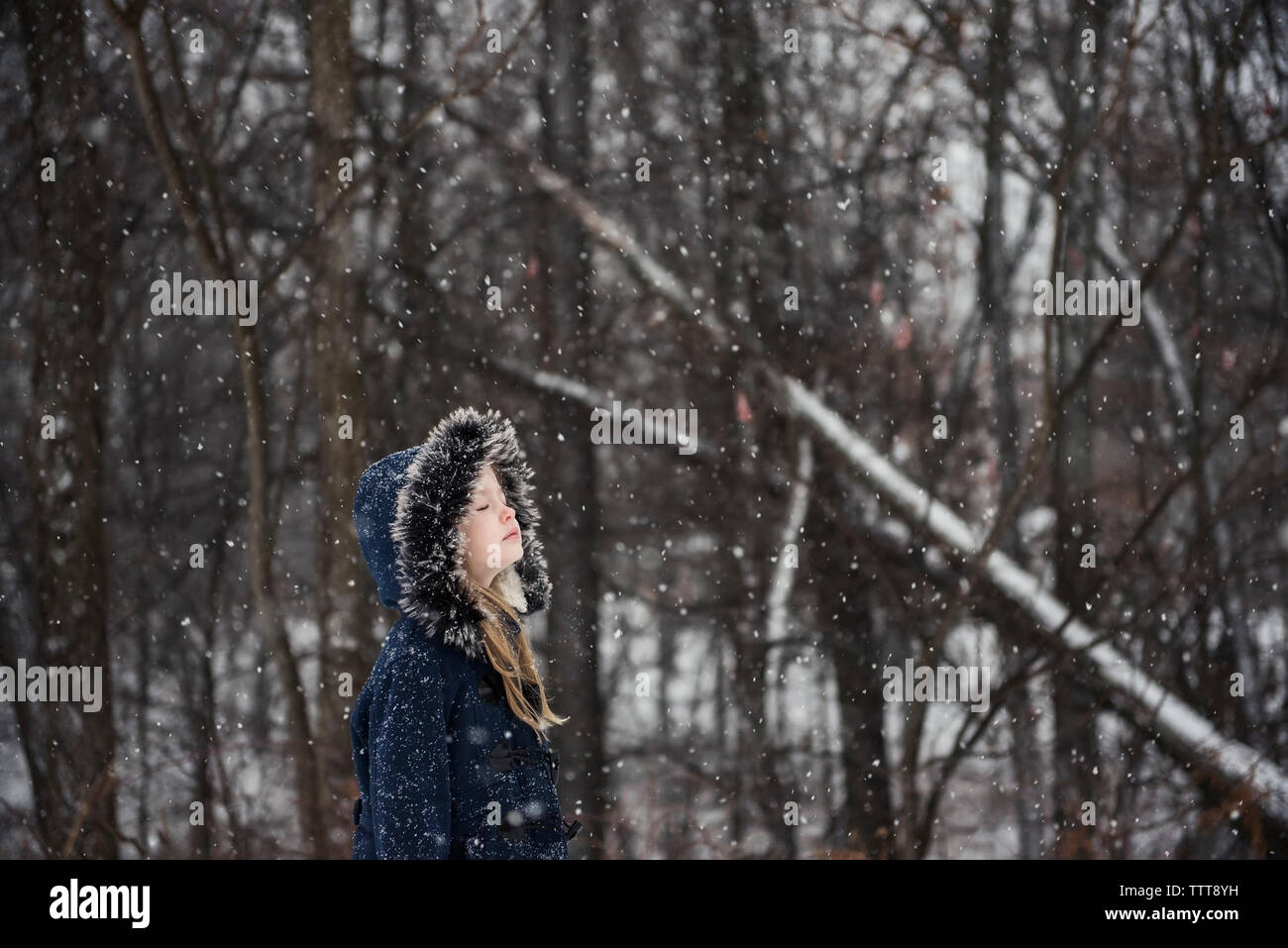Side view of girl with eyes closed wearing warm clothing while standing ...