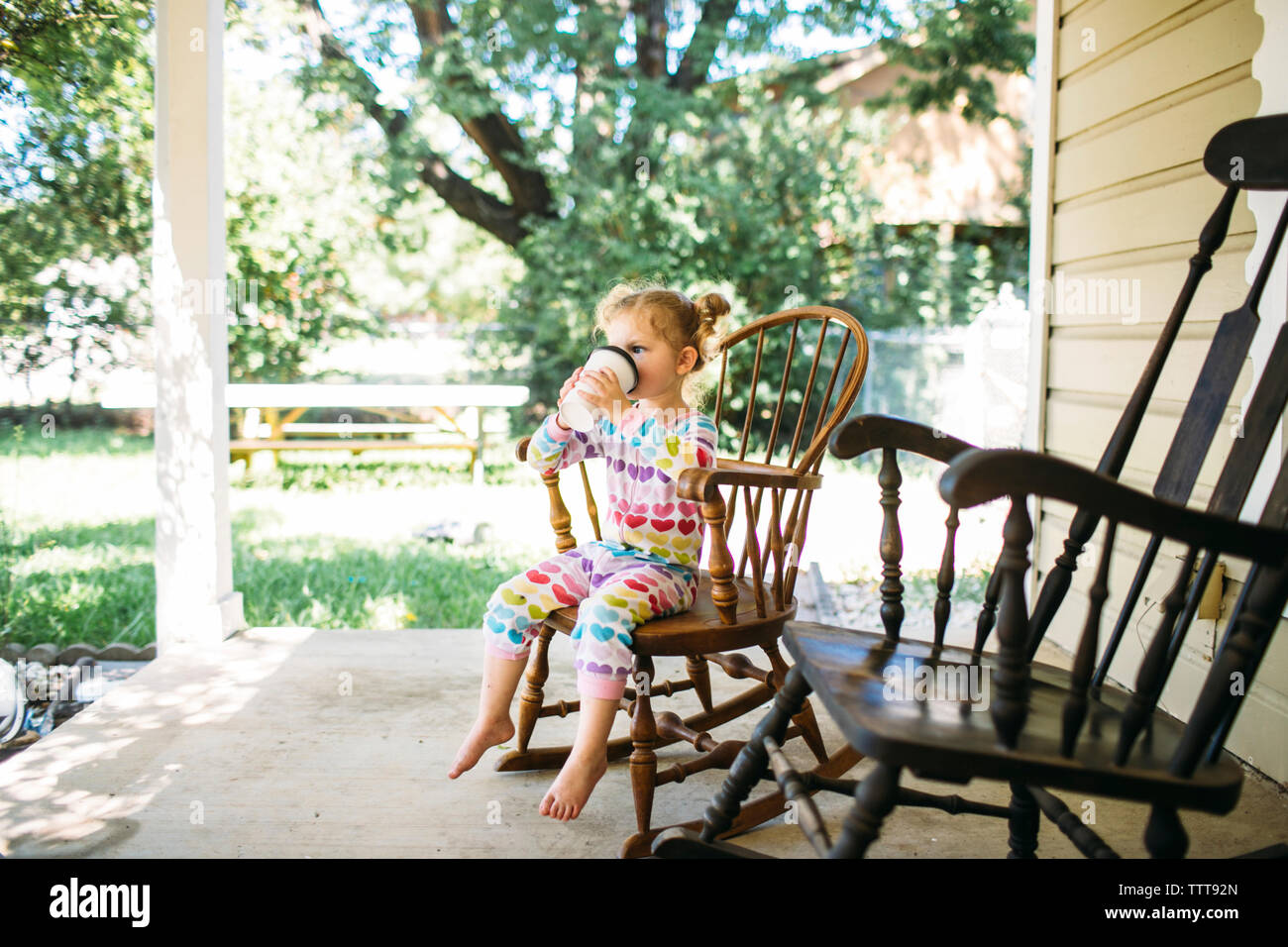 Girl having drink while sitting on rocking chair at porch Stock Photo ...
