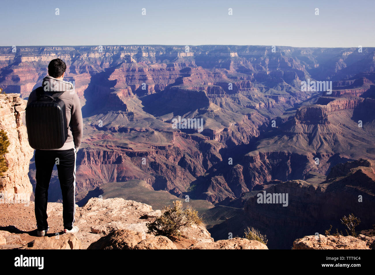 Hiker standing on cliff while looking at mountain range Stock Photo - Alamy