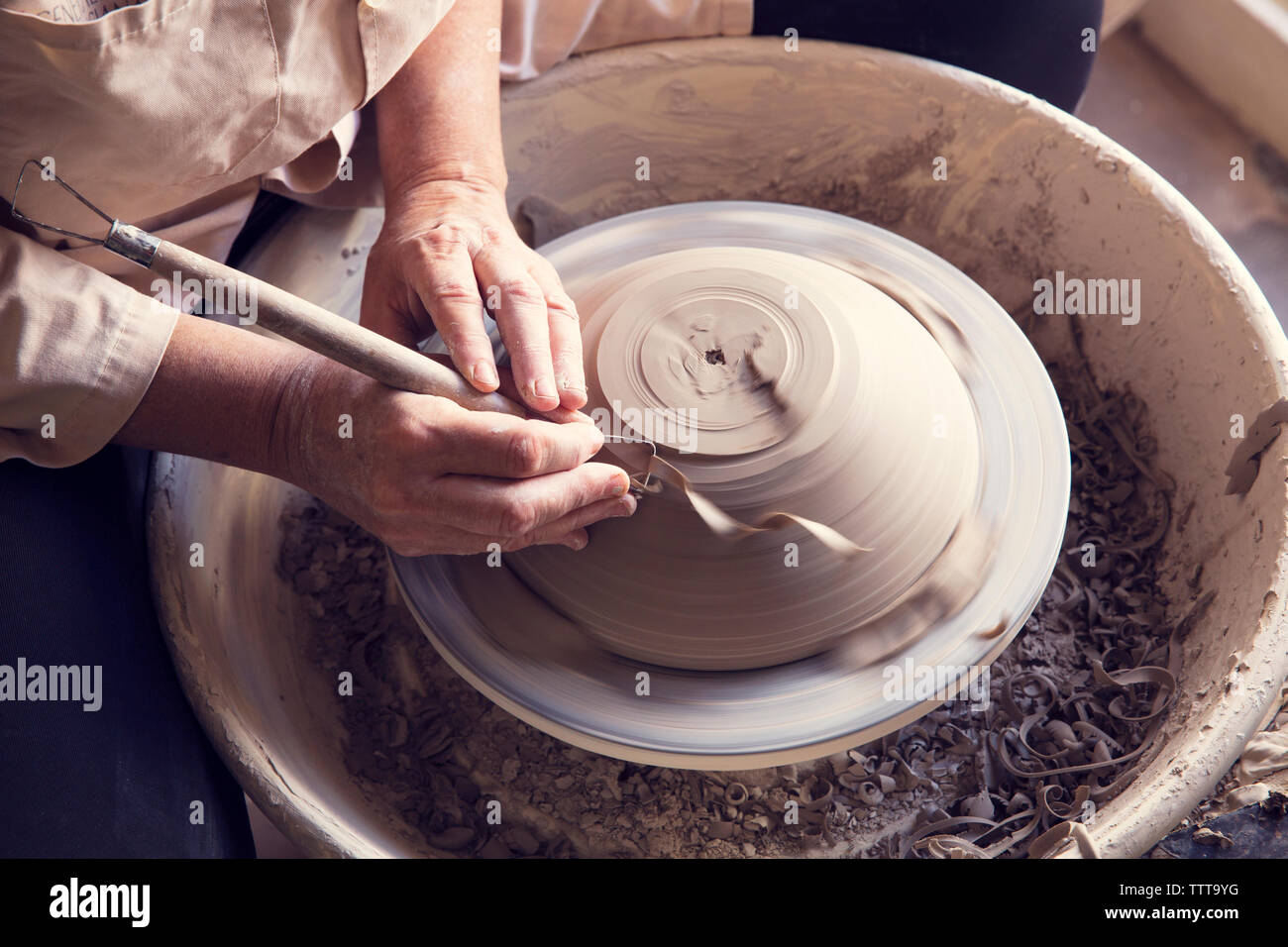 High angle view of woman molding shape to clay with work tool on ...