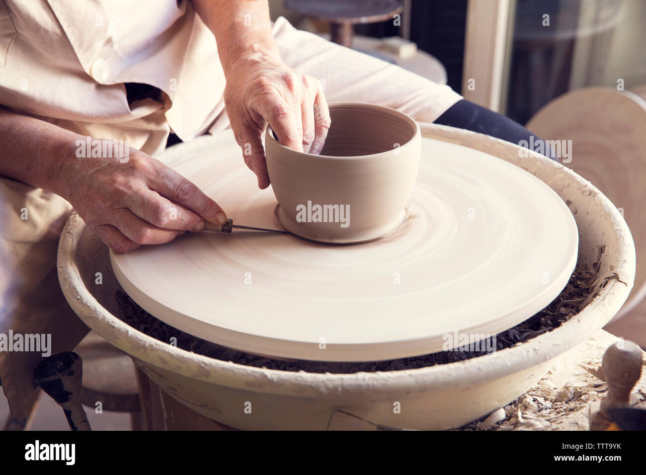 Woman molding shape to clay with work tool on pottery wheel Stock Photo ...