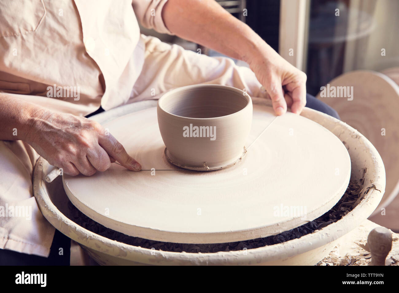 Midsection of woman molding shape to clay with work tool on pottery ...
