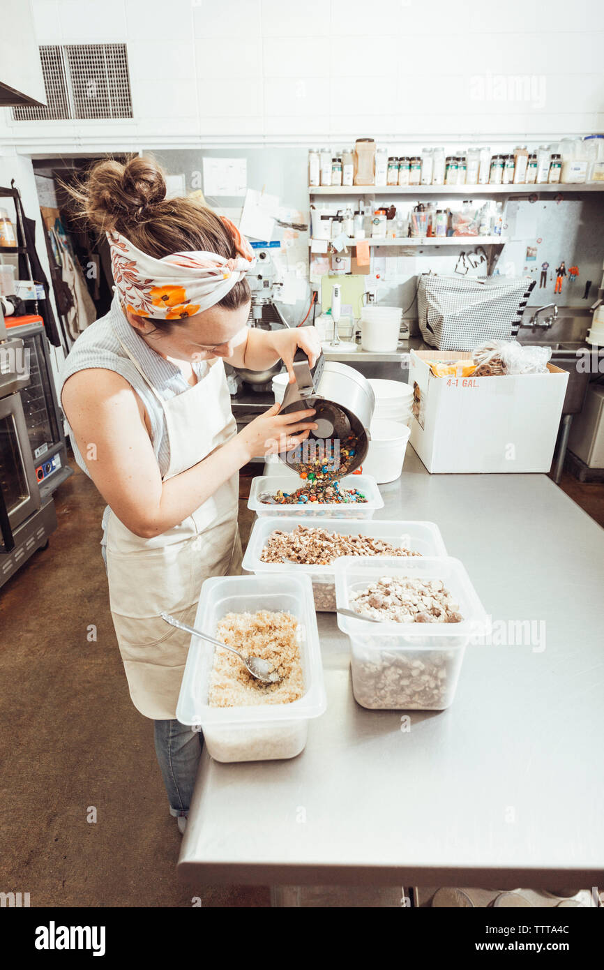 Woman pouring grinded ingredients in container while making ice cream ...