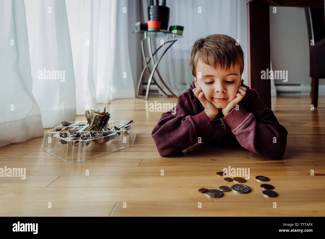 Boy with coins lying on floor at home Stock Photo - Alamy