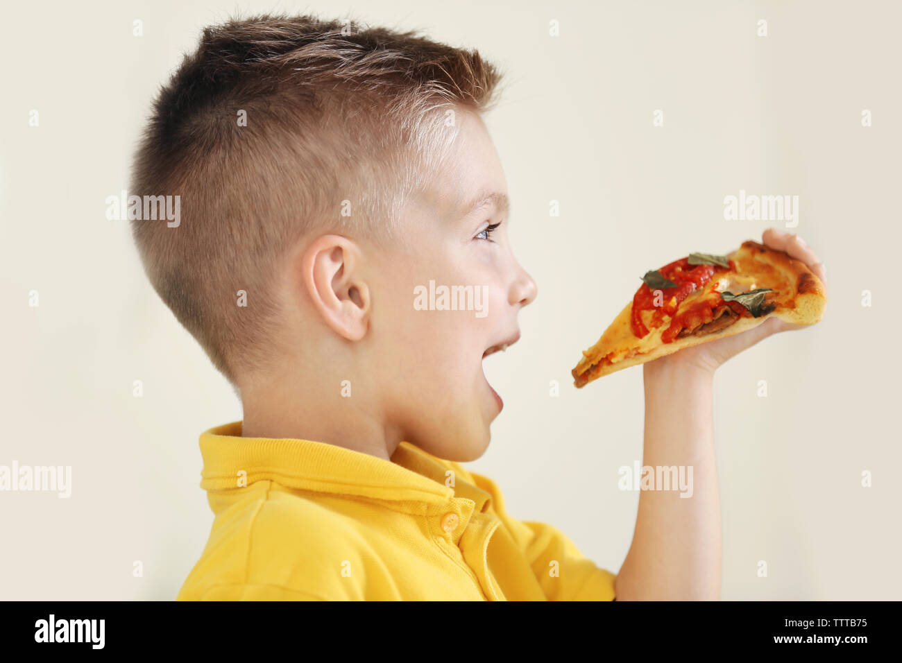 Cute boy eating pizza at home Stock Photo - Alamy