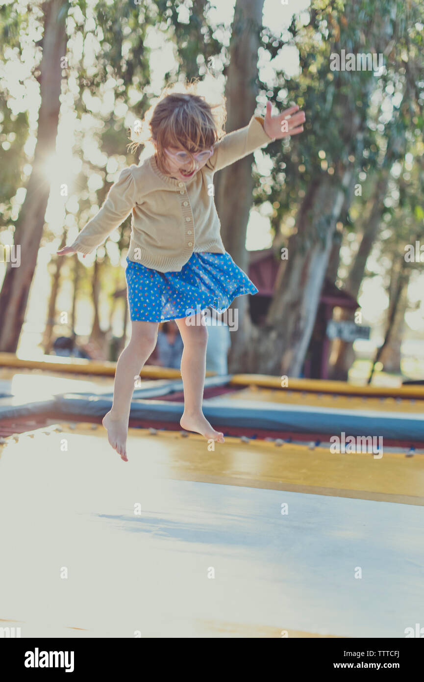 Full length of girl jumping on trampoline at playground Stock Photo - Alamy