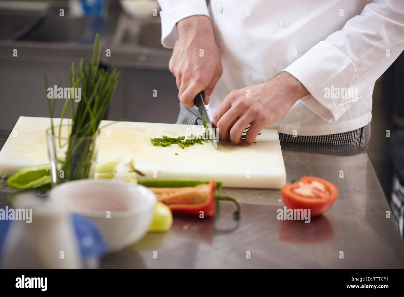 Close-up of chef chopping vegetables on cutting board at commercial ...