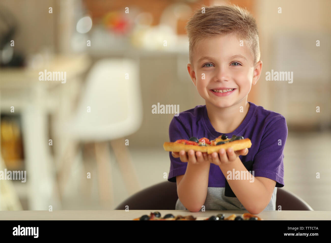 Cute boy eating pizza at home Stock Photo - Alamy