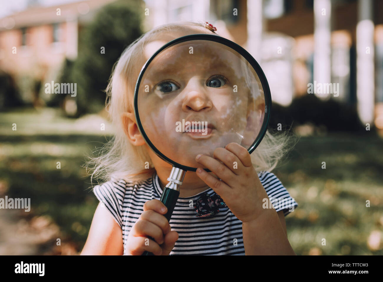 Portrait of playful baby girl with magnifying glass Stock Photo - Alamy