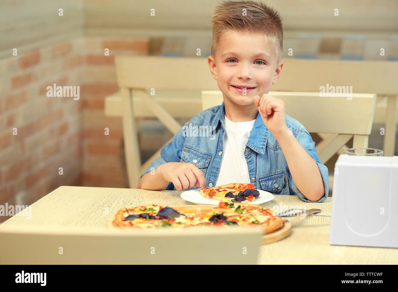 Cute boy eating pizza in restaurant Stock Photo - Alamy