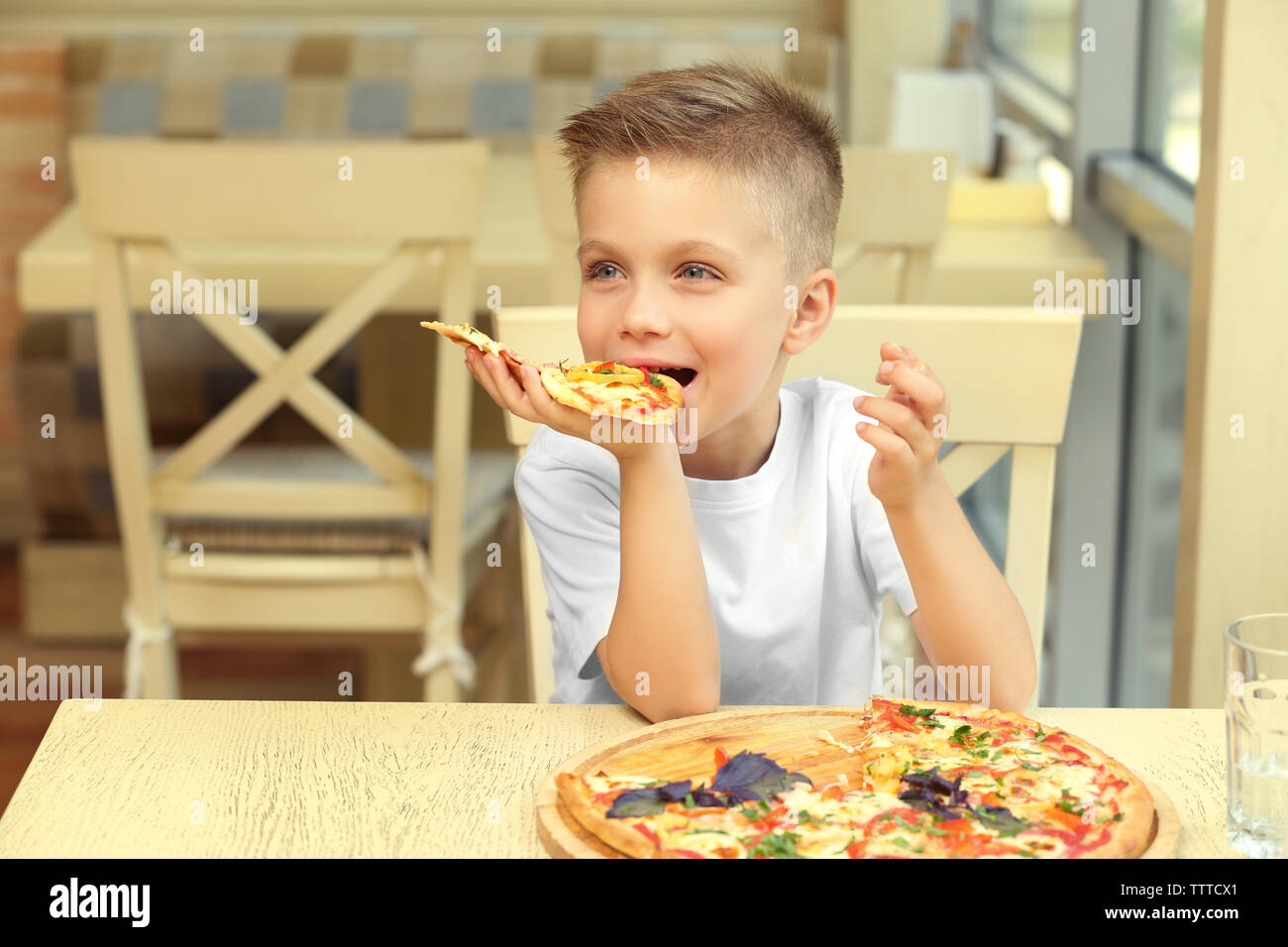Cute boy eating pizza in restaurant Stock Photo - Alamy