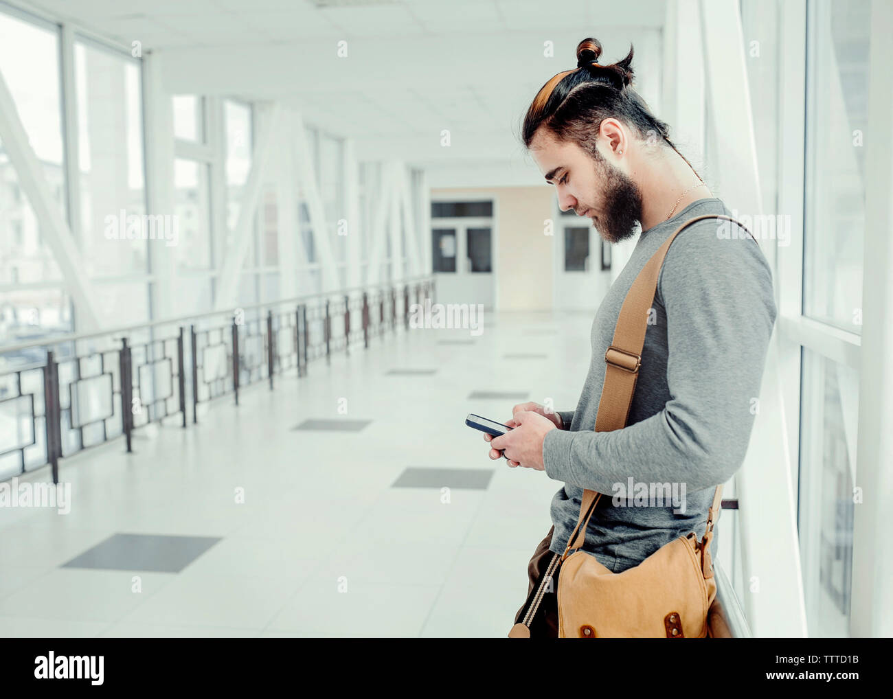 Side view of man using mobile phone while standing in corridor Stock ...