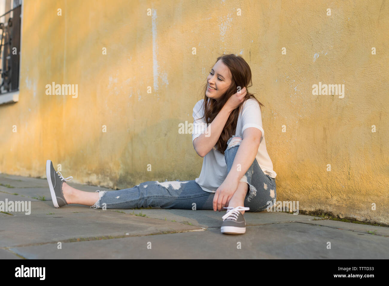 girl tossing her hair sitting on a side walk Stock Photo - Alamy