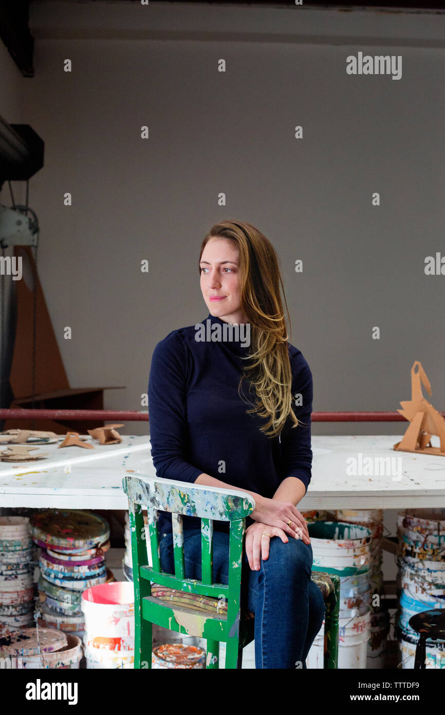 Thoughtful artist sitting on chair at table in art studio Stock Photo ...