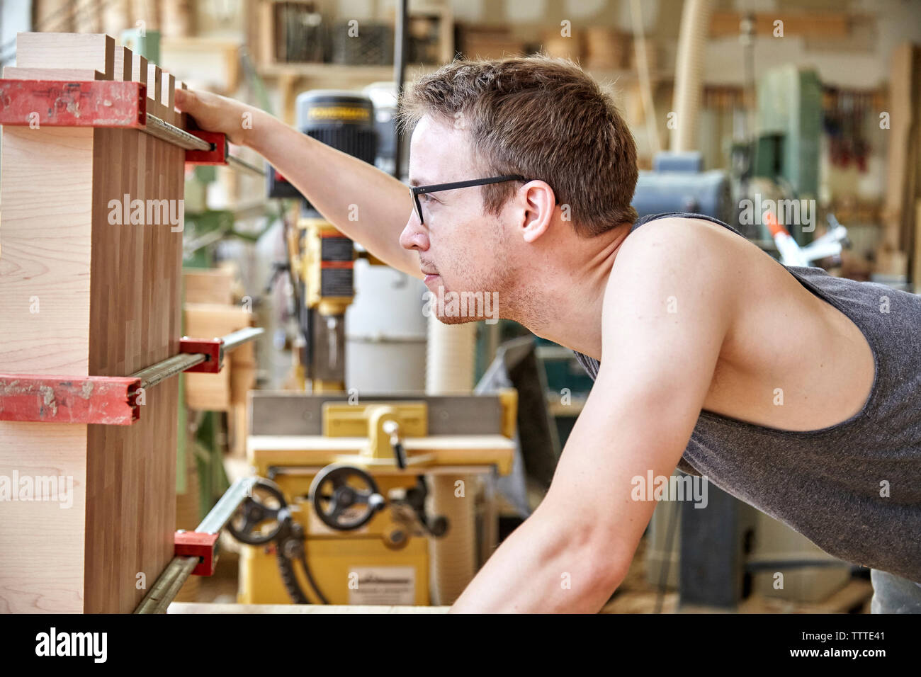 Side view of carpenter examining manufactured object in workshop Stock ...
