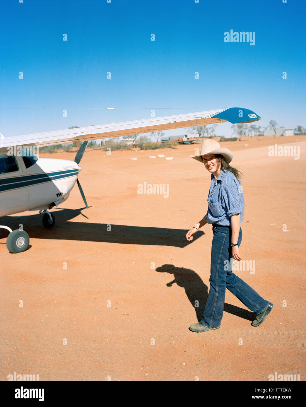 AUSTRALIA, Outback, portrait of a young female pilot walking towards ...