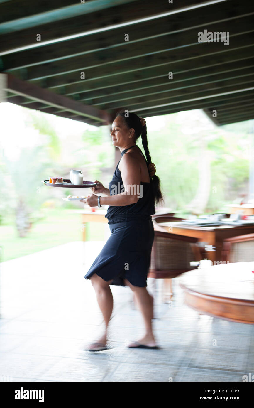 FRENCH POLYNESIA, Raiatea Island. A waitress serving breakfast at the ...