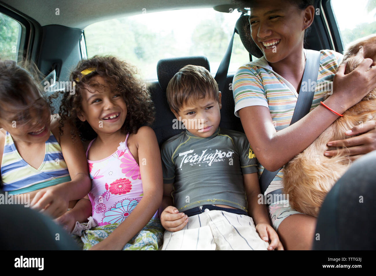 FRENCH POLYNESIA, Moorea Island. Kids riding in the back of a car with ...