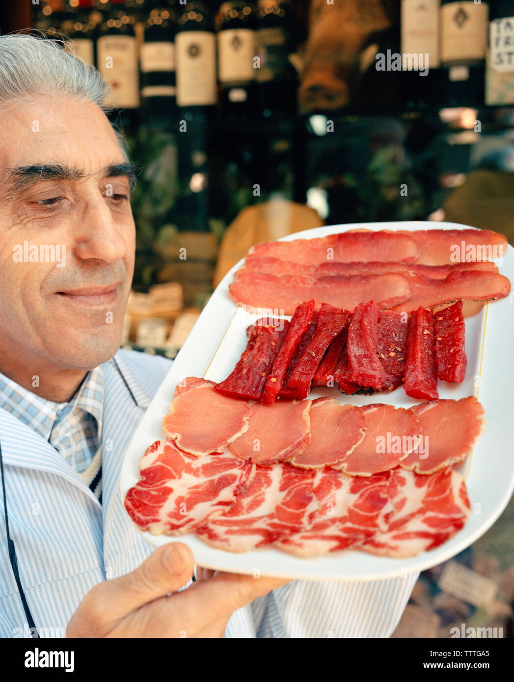 ITALY, Orvieto, Umbria, butcher Emilio Batalocco holding plate of cured ...