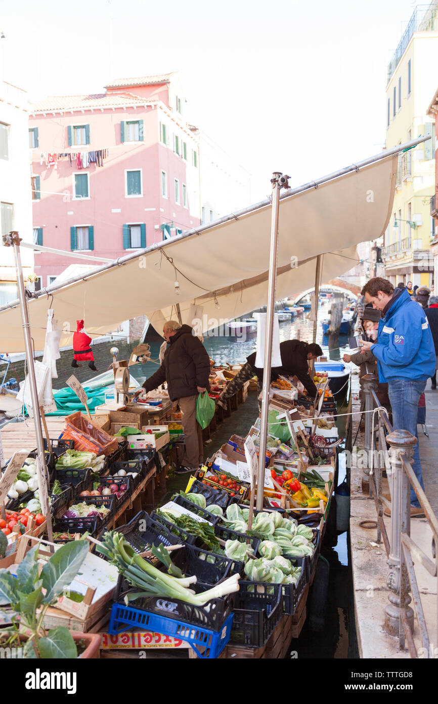 ITALY, Venice. Locals shopping at a floating produce market along a ...