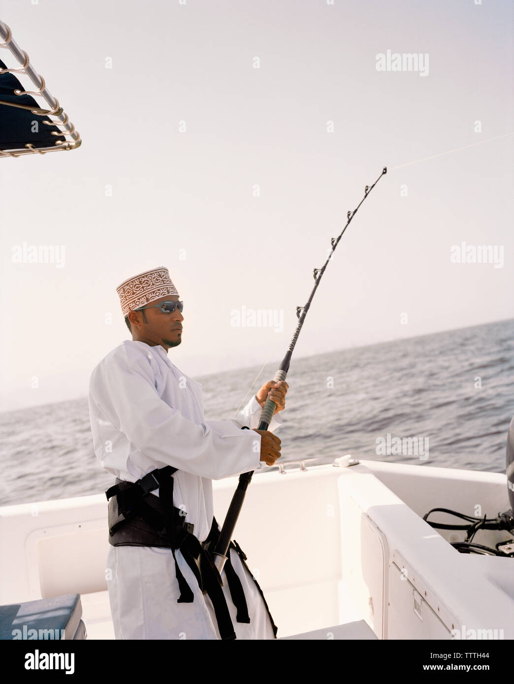 OMAN, Muscat, young man in traditional clothing fishing on boat Stock ...
