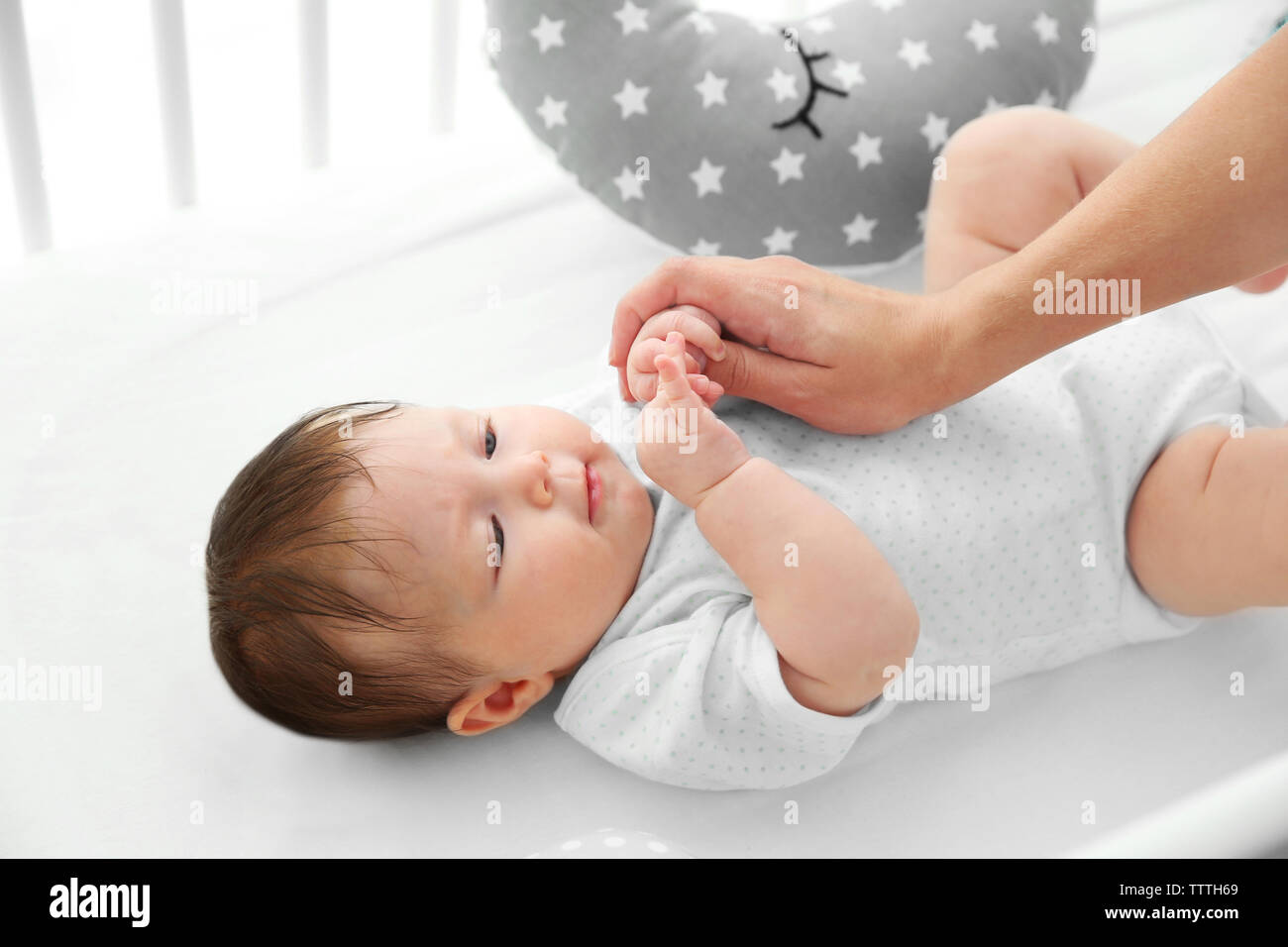 Cute baby in bed with mother hand Stock Photo - Alamy