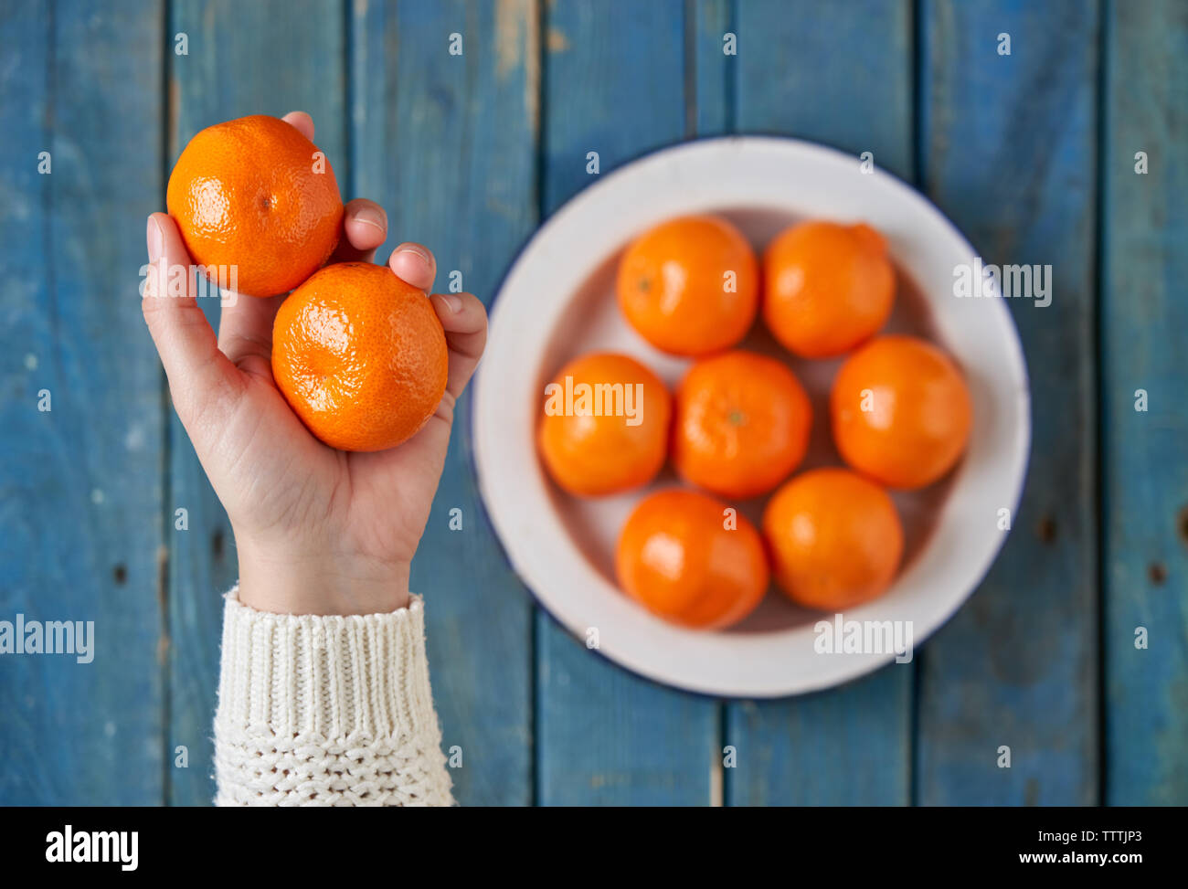 Hand holding some tangerines over blue table Stock Photo - Alamy