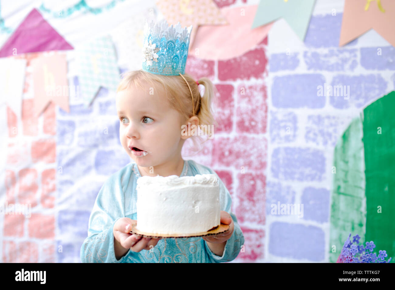 Girl holding cake while standing against castle painting during ...