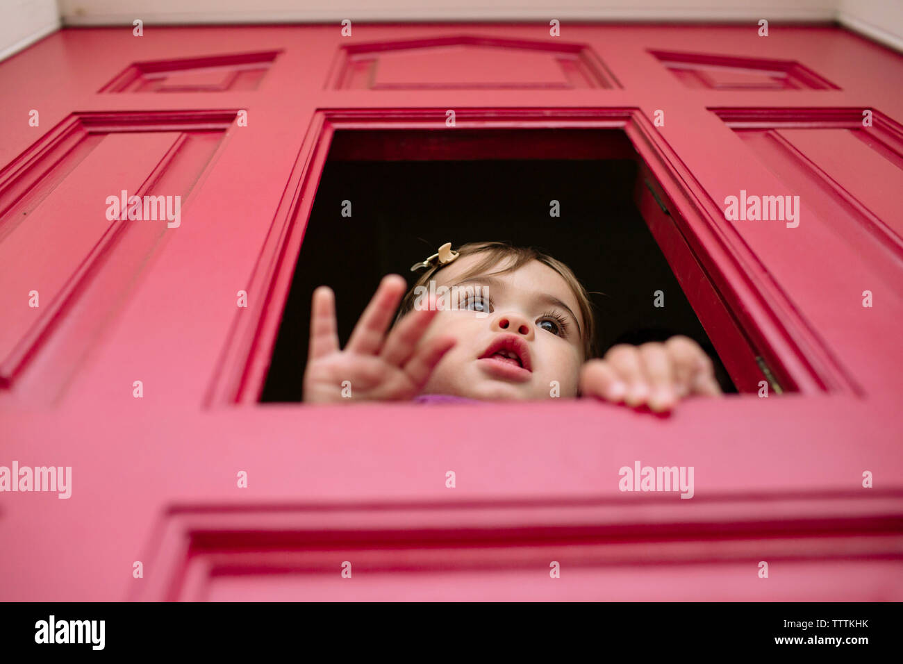 Low angle view of cute baby girl looking through window Stock Photo - Alamy