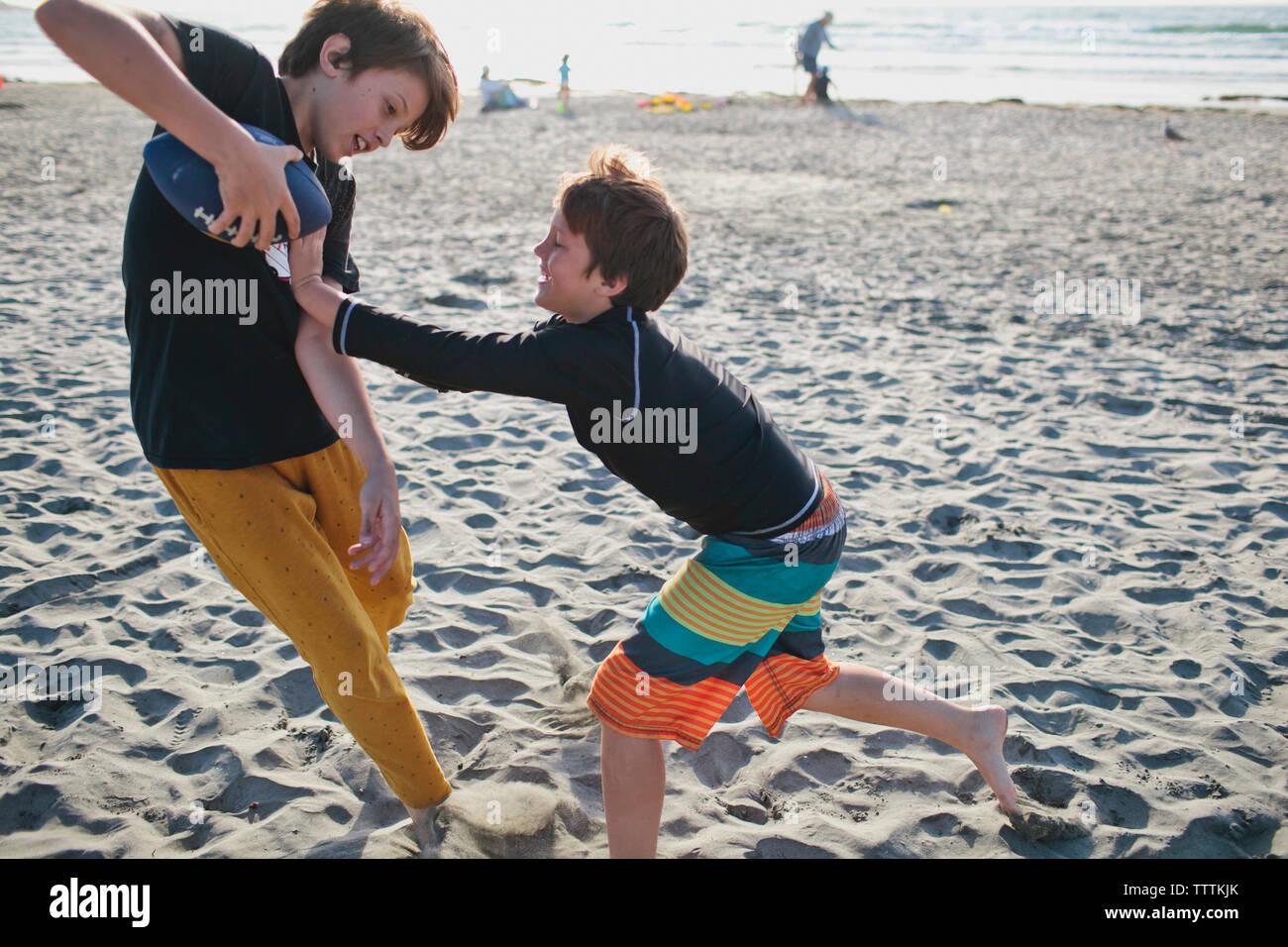 Playful brothers playing with rugby ball at beach Stock Photo - Alamy