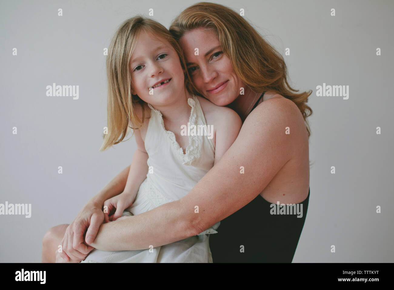 Portrait of confident mother and daughter against white background ...