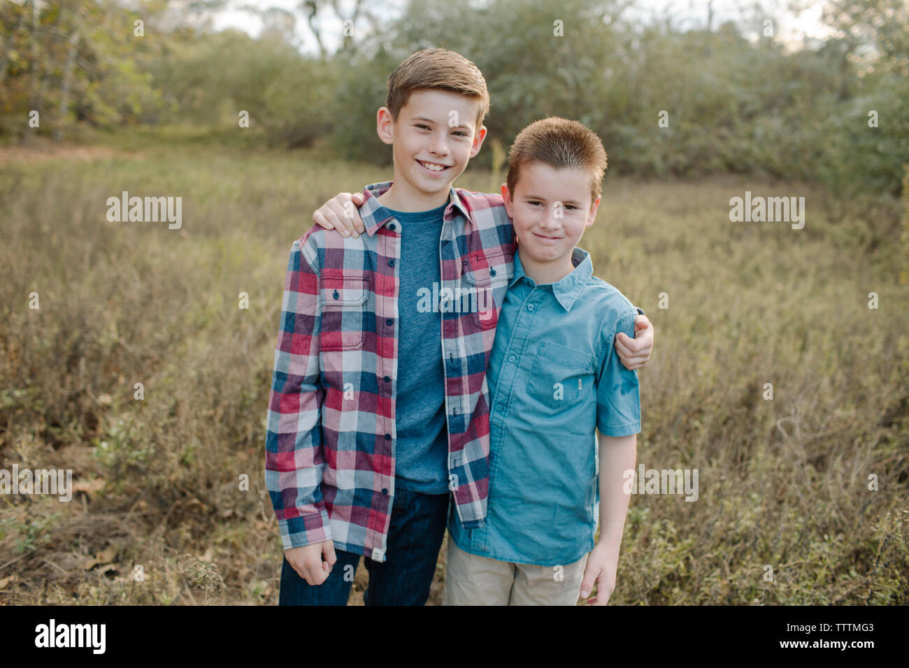 Portrait of smiling brothers standing on field Stock Photo - Alamy