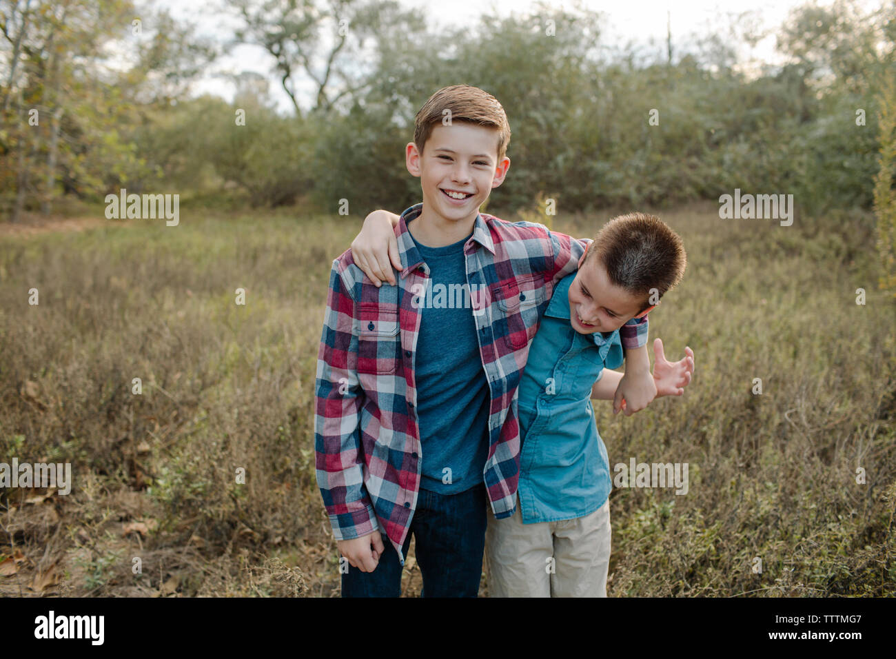 Happy brothers standing on field Stock Photo - Alamy