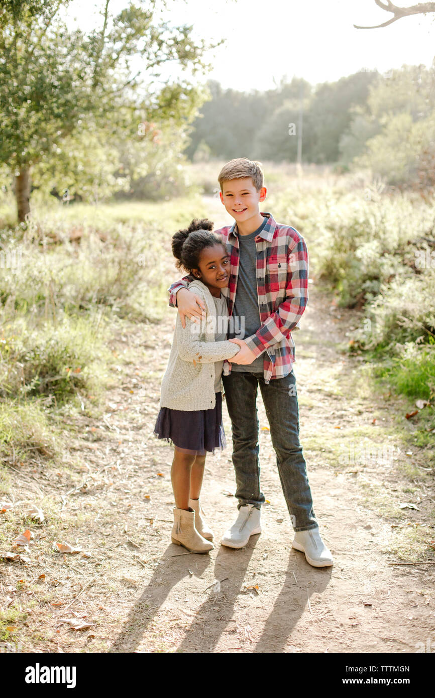 Portrait of brother and sister standing on field at park Stock Photo ...