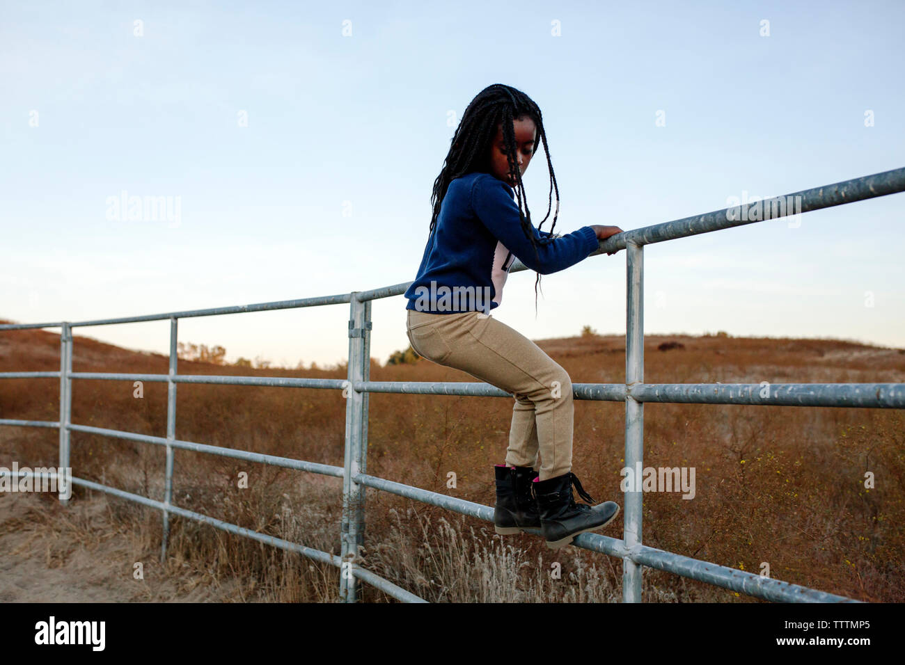 Side view of girl climbing railing against sky Stock Photo - Alamy