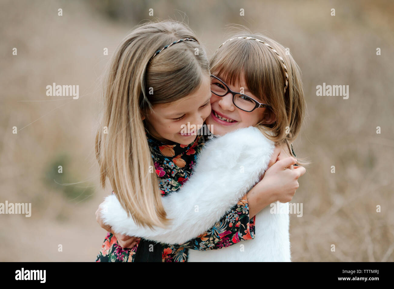 Happy sisters embracing while standing on field Stock Photo - Alamy