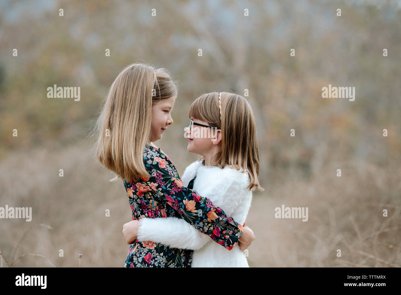 Happy sisters looking at each other while embracing on field Stock ...